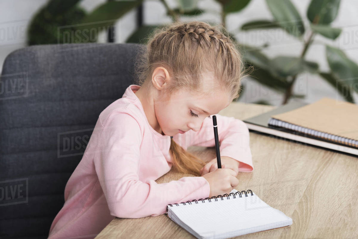 Adorable child sitting at desk and studying at home - Stock Photo ...