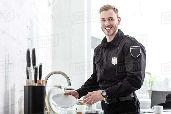 Handsome police officer washing dishes at kitchen - Royalty-free Stock ...