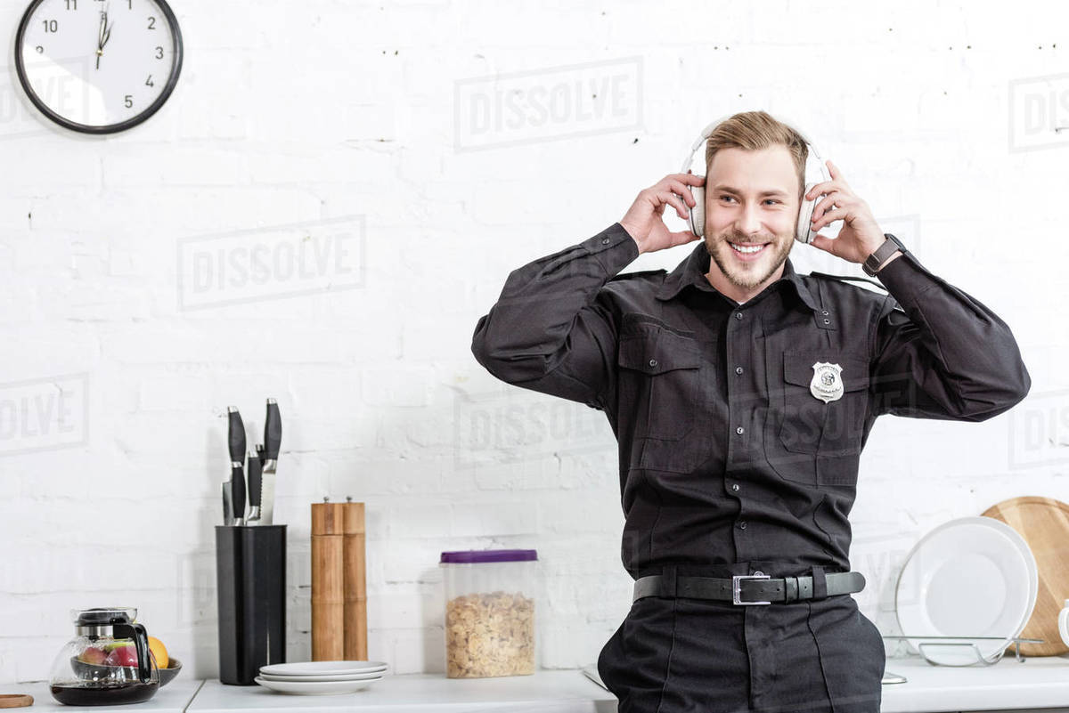 Handsome policeman listening to music at kitchen - Stock Photo - Dissolve