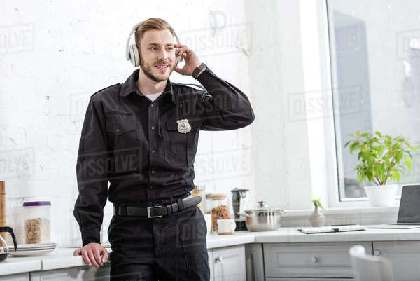 Handsome policeman listening to music with headphones in morning ...