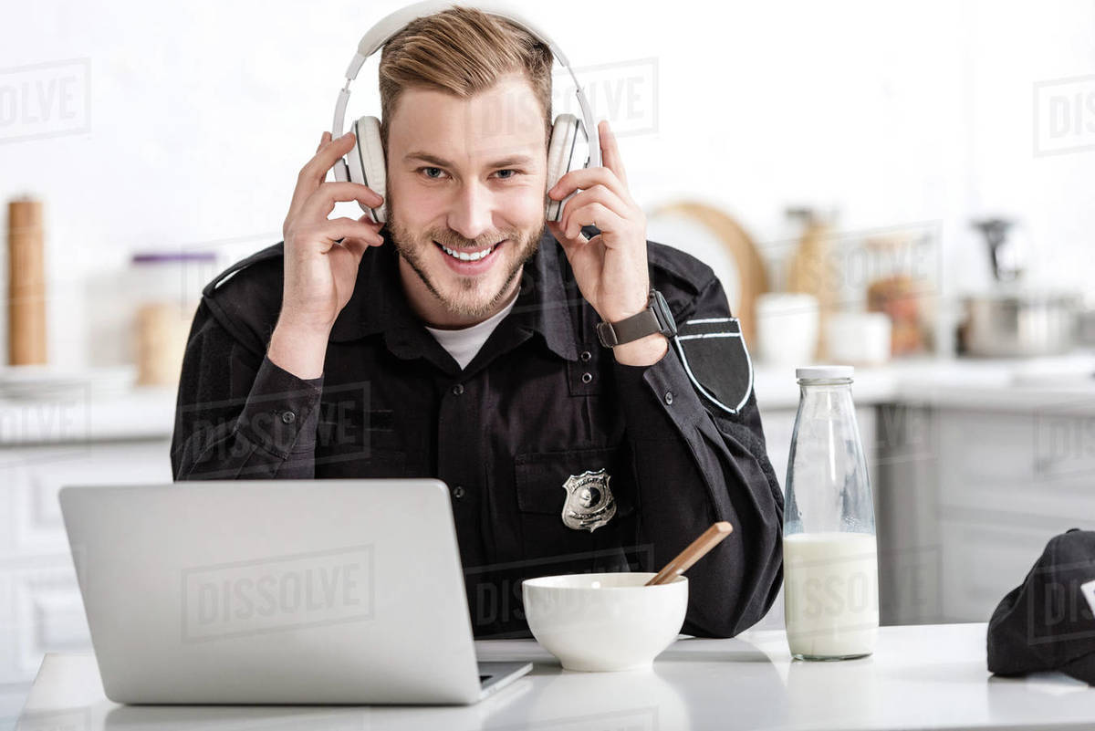 smiling police officer having breakfast and listening to music with ...