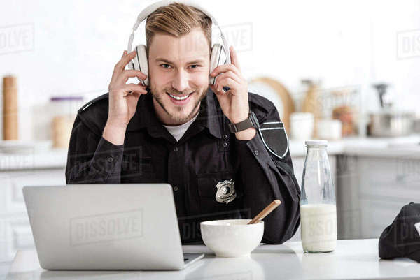 smiling police officer having breakfast and listening to music with ...