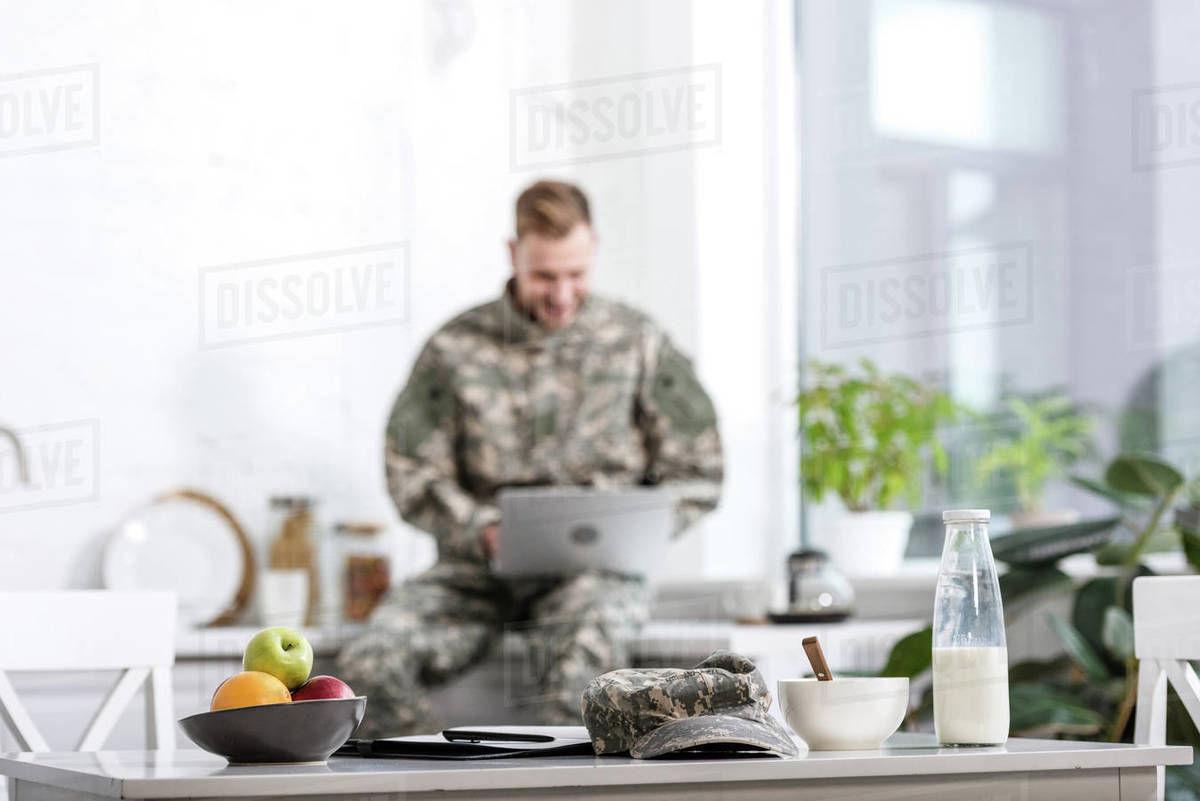 selective focus of army soldier working on laptop in kitchen - Royalty ...