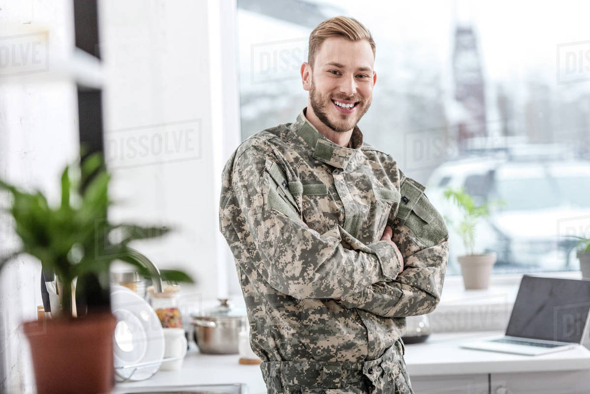 handsome soldier smiling and looking at camera in kitchen - Royalty ...