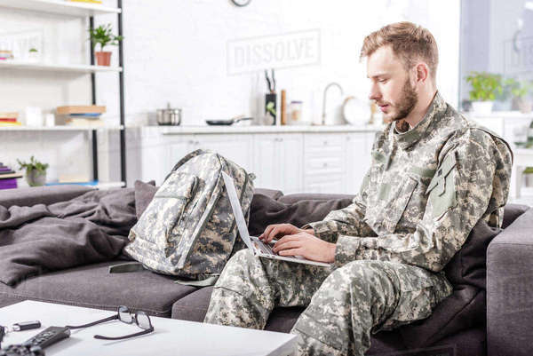 focused army soldier using laptop on couch at home - Royalty-free Stock ...
