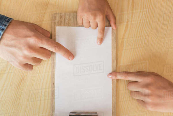Cropped shot of young family pointing at blank paper on clipboard ...