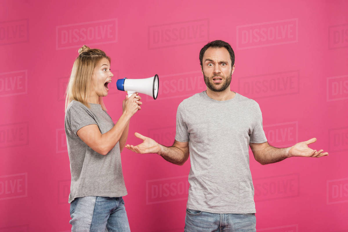 Angry woman shouting with megaphone at confused man with shrug gesture ...