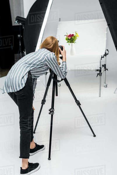 Back view of young woman shooting beautiful flowers in professional ...
