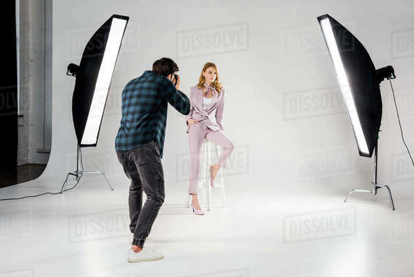 Back view of photographer shooting beautiful young female model in ...