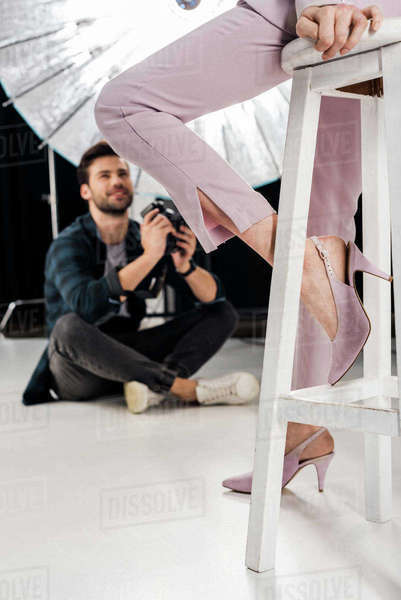 Cropped shot of smiling photographer sitting and photographing stylish ...