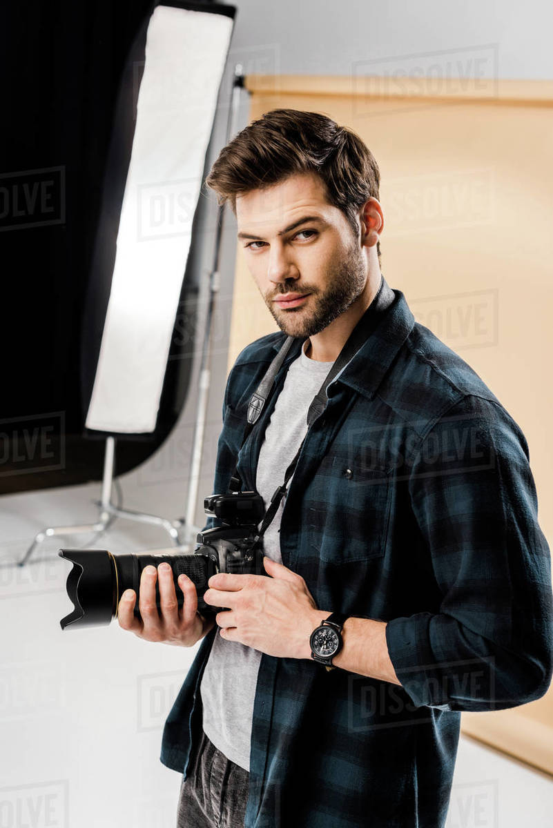 Handsome young photographer looking at camera in professional photo ...
