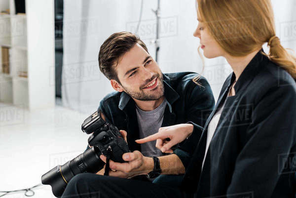 Happy young photographer and model using photo camera together in ...