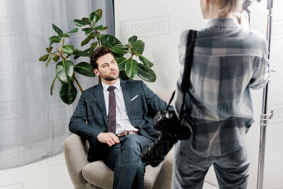 Back view of photographer with camera looking at handsome businessman ...