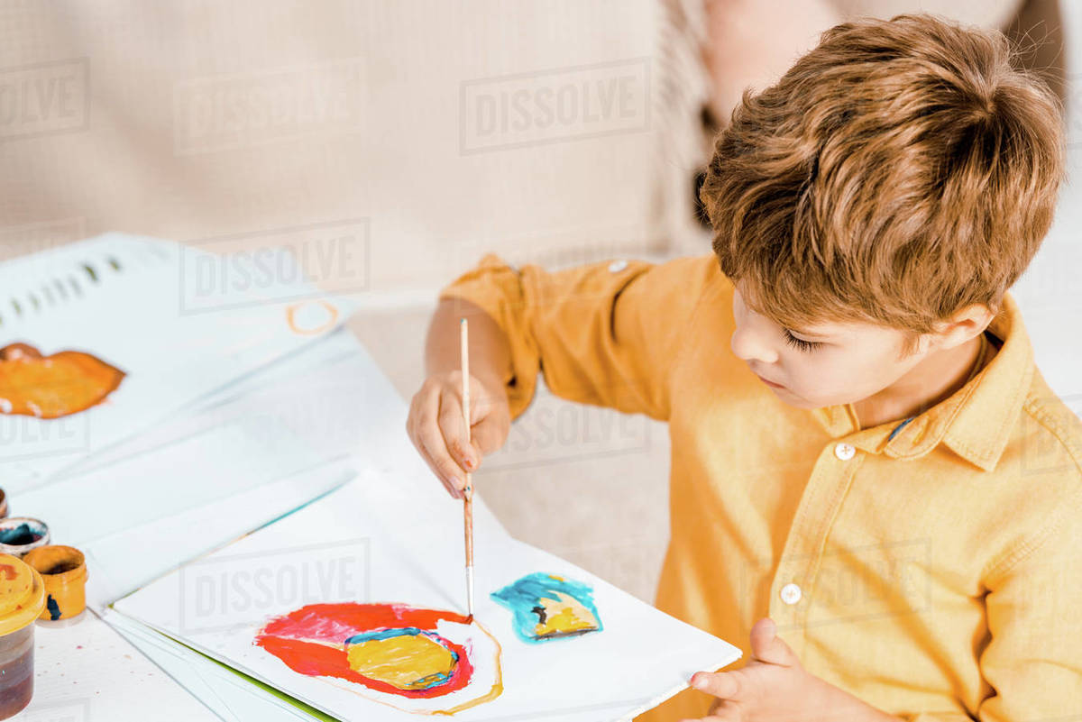 Cute little boy painting colorful picture at home - Stock Photo - Dissolve