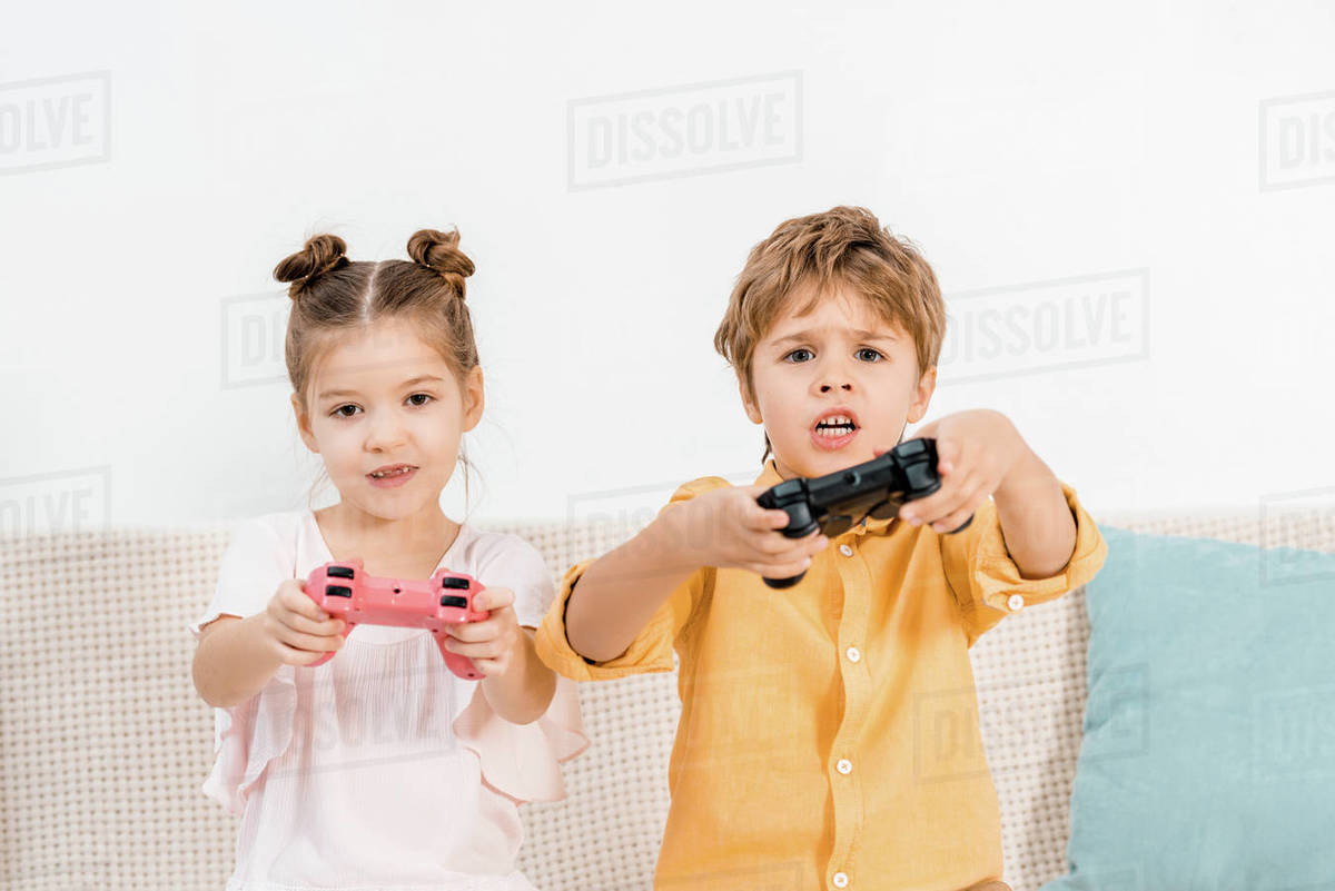 Adorable kids playing with joysticks and looking at camera - Royalty ...