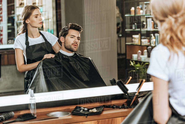 female hairstylist cutting hair to handsome young man in beauty salon ...