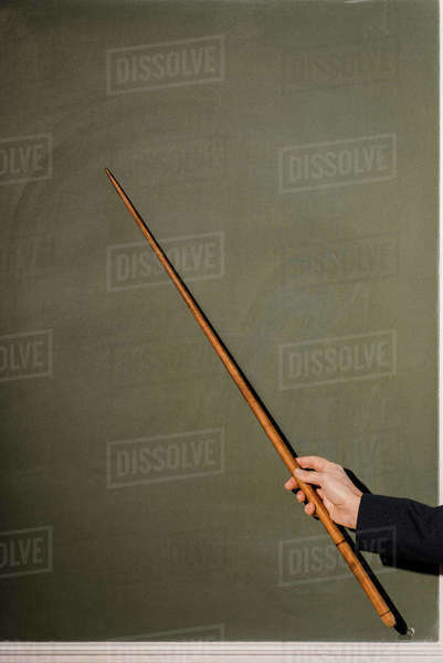 Cropped view of female teacher holding wooden pointer on chalkboard ...