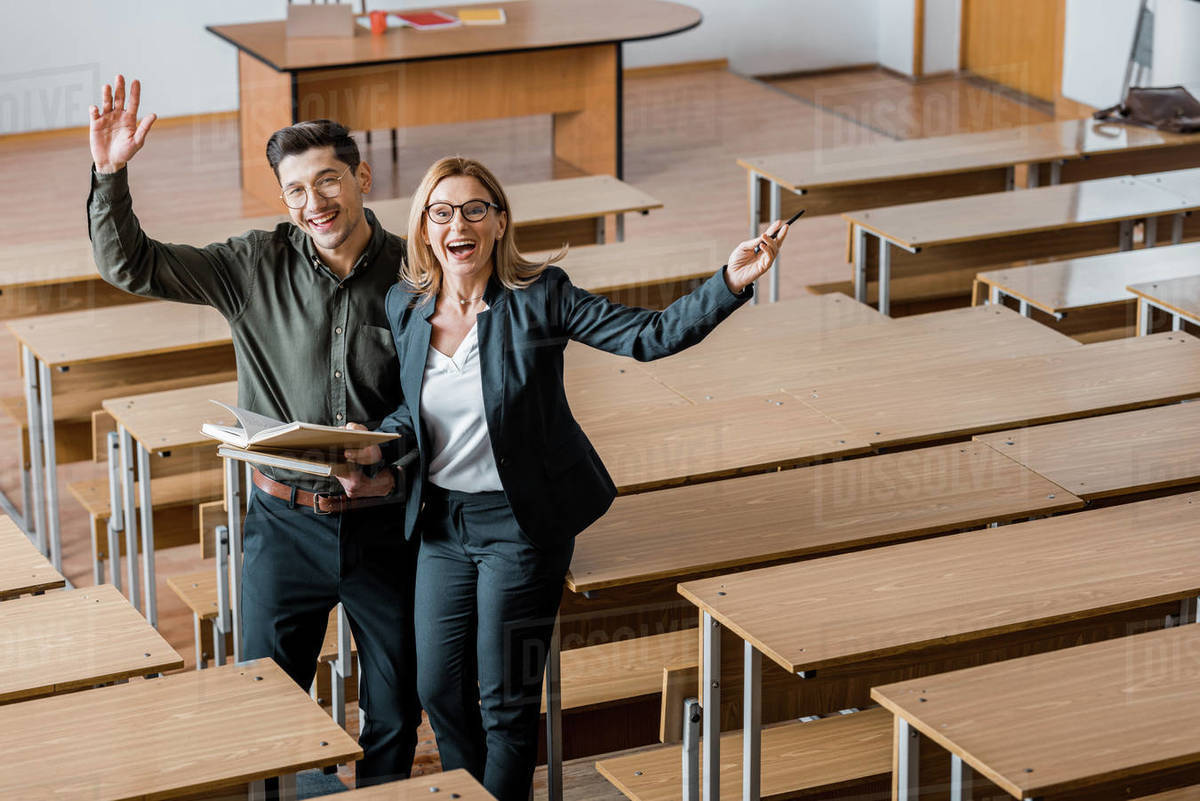 Cheerful male student and female teacher with outstretched hands ...