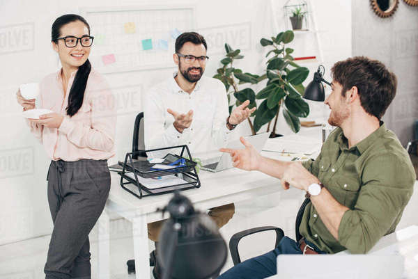 Happy office managers holding coffee cup and talking in office ...