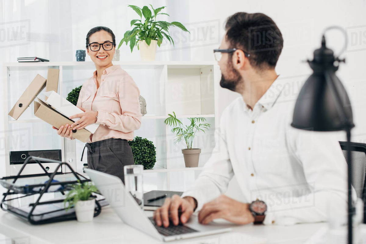 Selective focus of female manager standing with folders and looking at ...