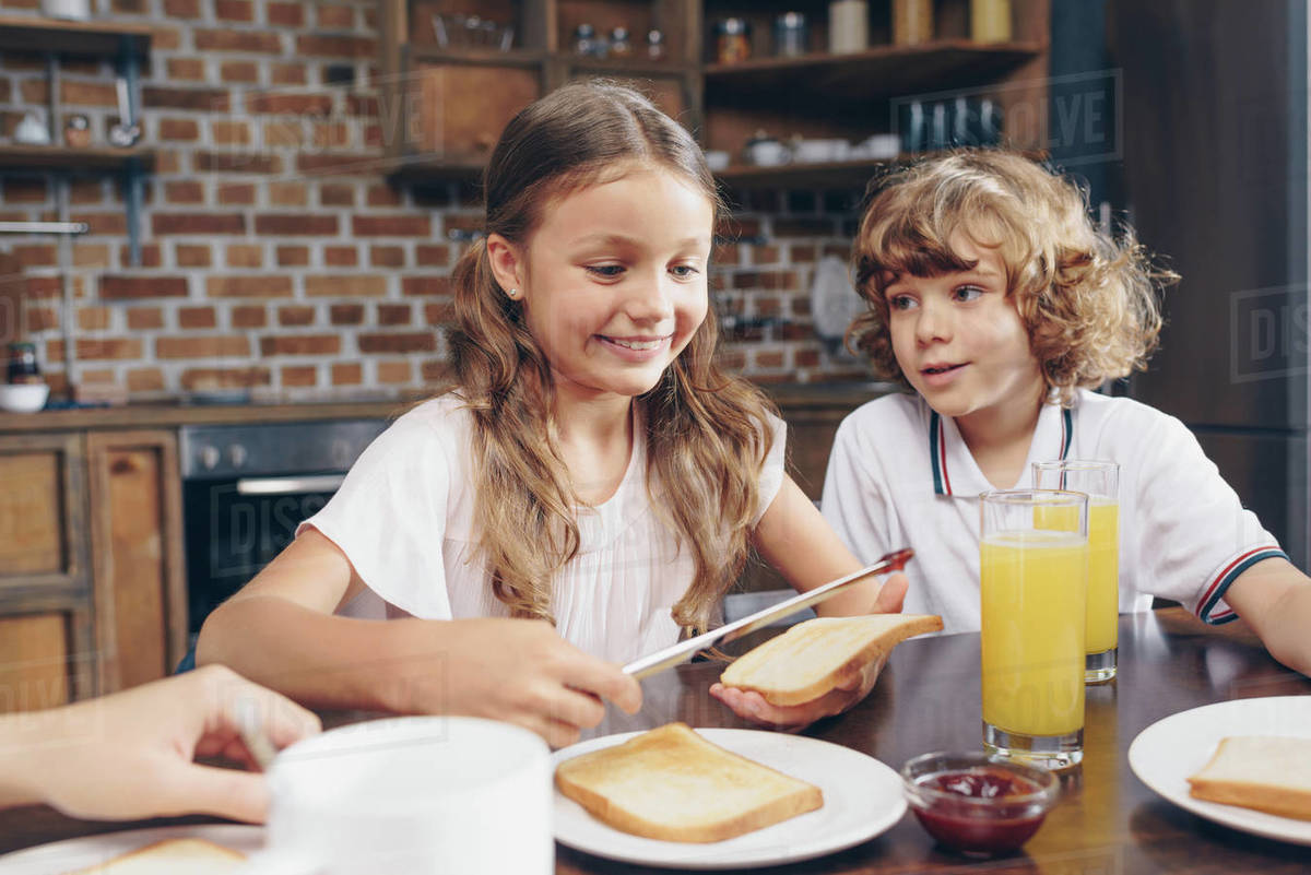Happy little kids having breakfast before school - Stock Photo - Dissolve