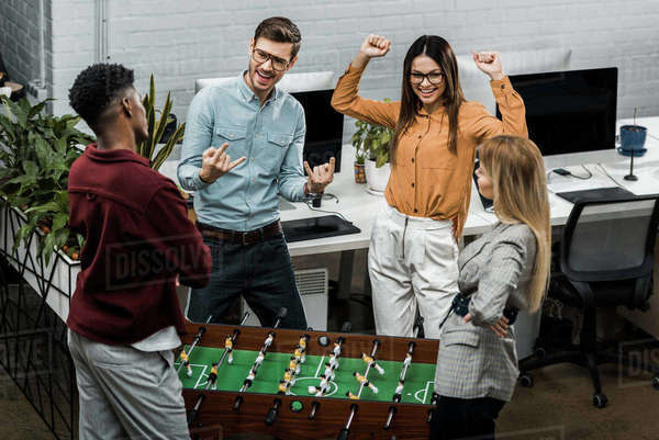 Happy multicultural business colleagues playing table football together ...