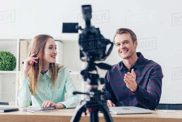 Selective focus of smiling video bloggers recording vlog in office ...