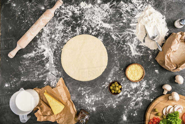 Top view of pizza dough with ingredients on grey background - Stock ...