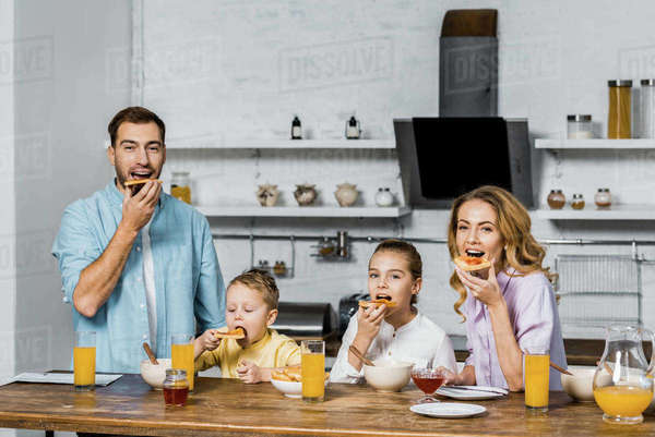 Happy family eating toasts with jam at table in kitchen - Royalty-free ...