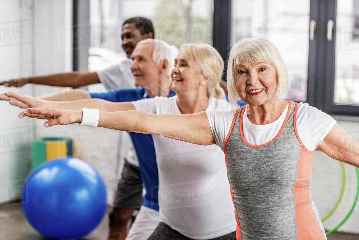 Happy senior multiethnic sportspeople synchronous exercising at sports ...