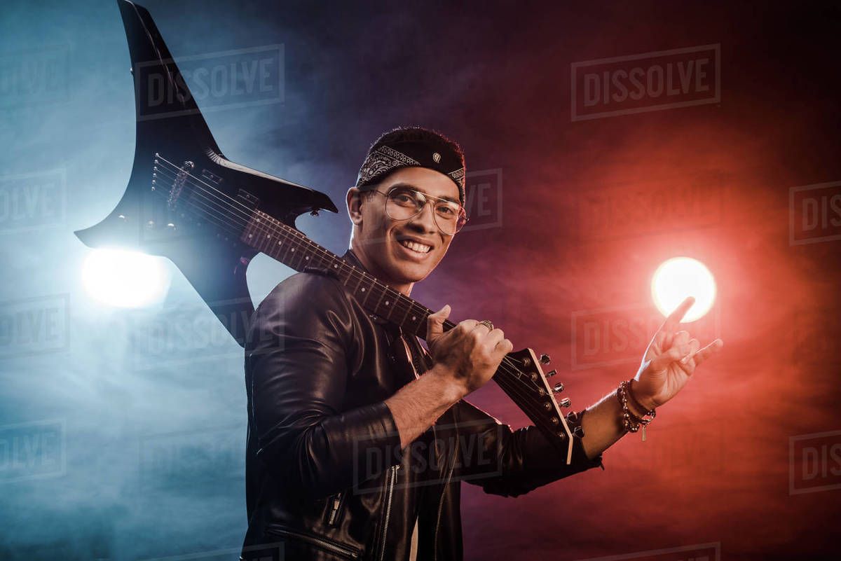 Male rocker in leather jacket posing with electric guitar and doing ...
