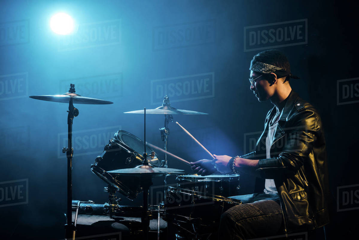 Side view male musician in leather jacket playing drums during rock ...