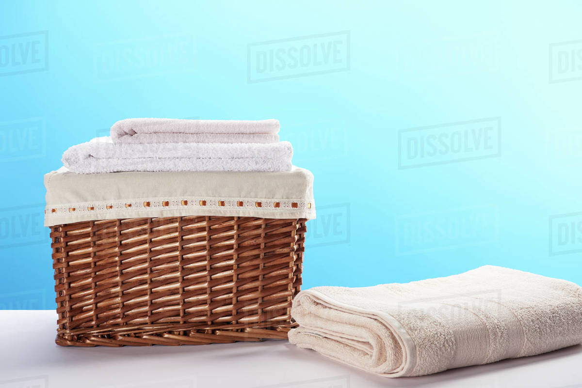 Laundry basket and clean soft towels on blue - Stock Photo - Dissolve
