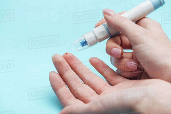 Cropped view of female hands making glucose level test with needle on ...