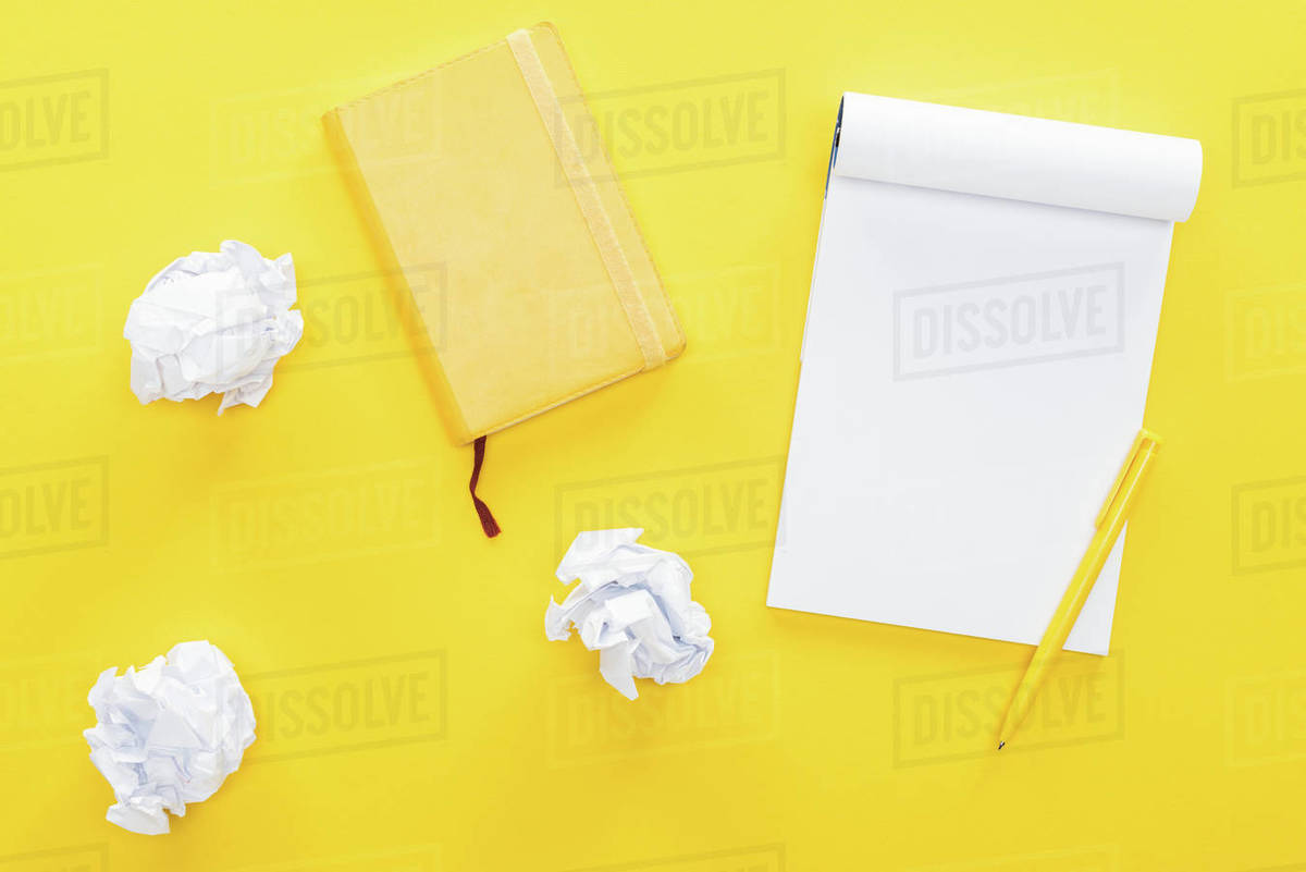 Blank notebook and crumbled paper balls on yellow background - Stock ...