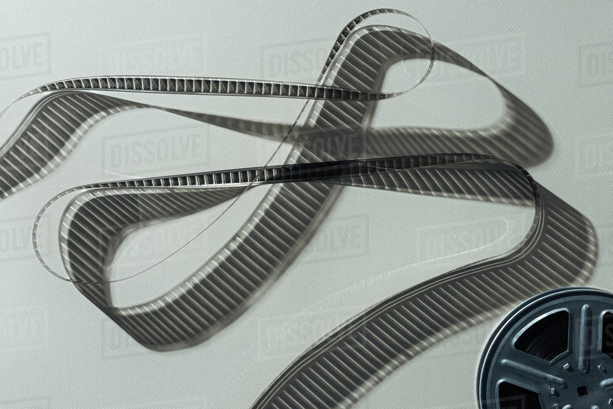 Top view of film reel with twisted cinema tape on grey background ...