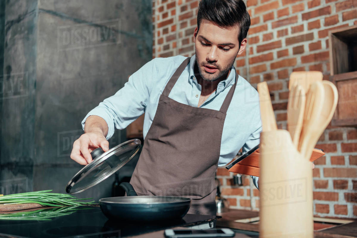 Handsome young man cooking with tablet - Royalty-free Stock Photo ...