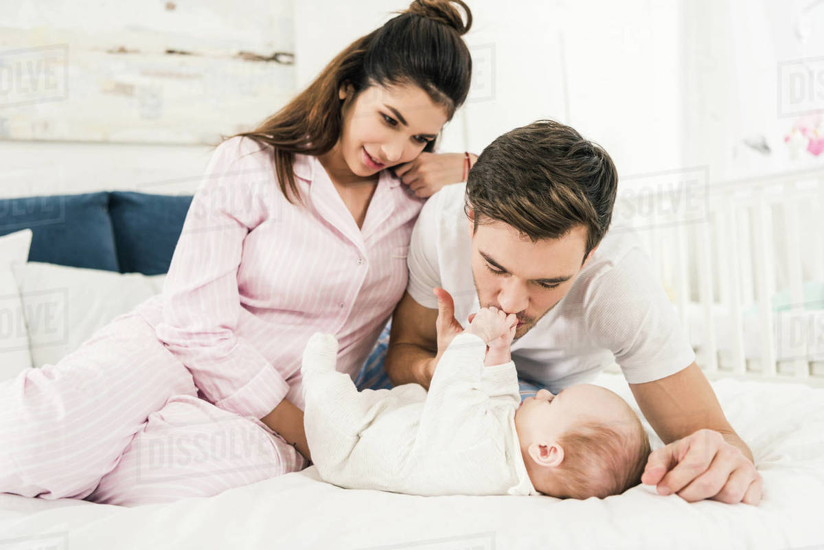 Happy parents resting on bed together with cute baby at home - Royalty ...