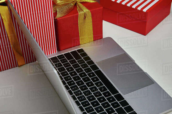 Opened laptop near wrapped colorful giftboxes - Stock Photo - Dissolve