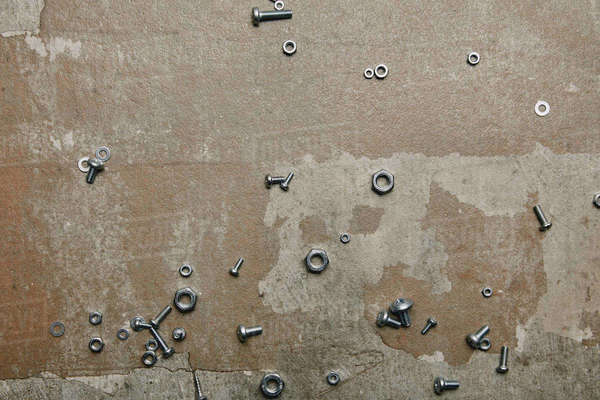 Top view of screws and bolts scattered on the background of old surface ...