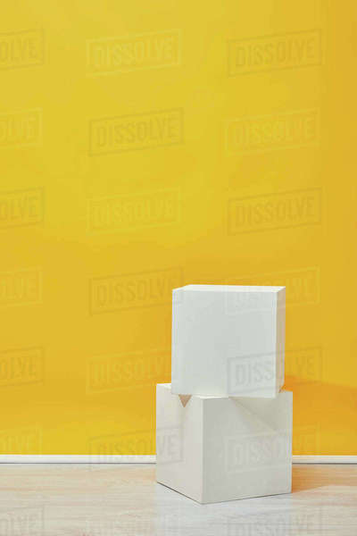 Two plaster cubes arranged vertically near yellow wall - Royalty-free ...