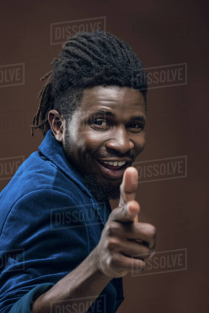 Smiling African American man pointing on camera isolated on brown ...