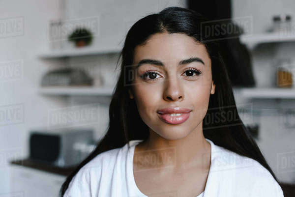Portrait of beautiful mixed race girl in white robe looking at camera ...