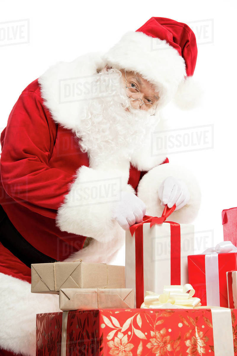 Happy Santa Claus standing with a pile of Christmas gifts isolated on ...