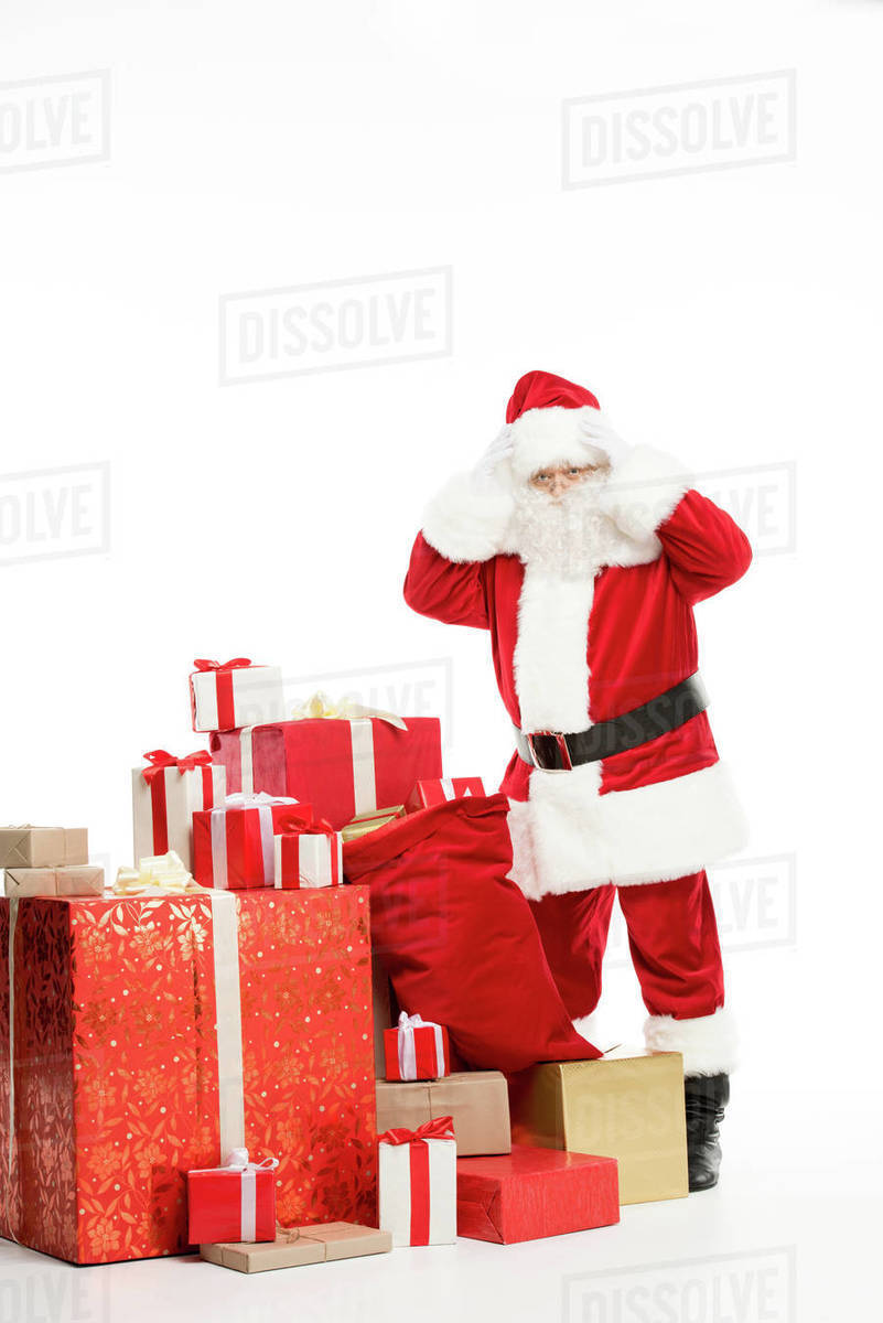 Shocked Santa Claus standing with a pile of Christmas gifts isolated on ...