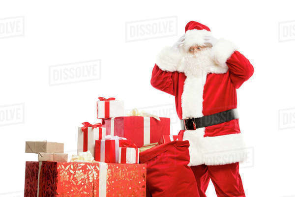 Shocked Santa Claus standing with a pile of Christmas gifts isolated on ...