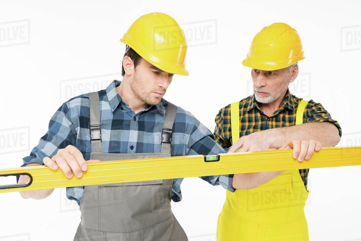 Two serious workmen working with level tool isolated on white - Royalty ...
