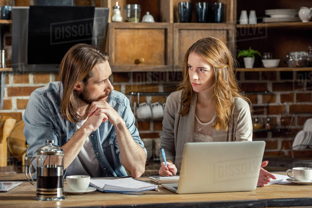 Young couple working together with papers and laptop at home - Stock ...