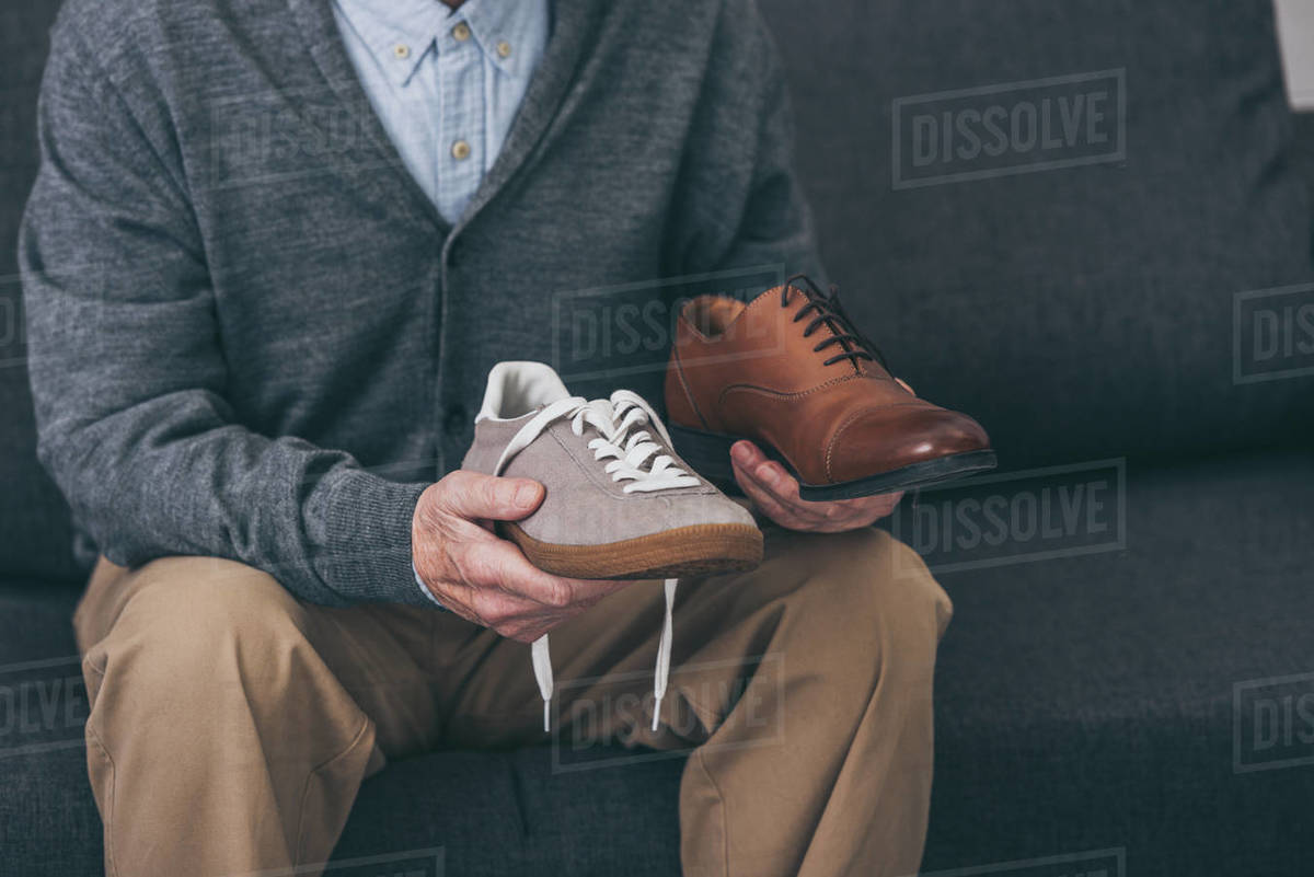 Cropped view of senior man holding classic and modern shoes in hands ...