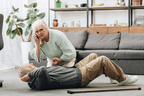 Senior woman holding hand of dying old man with walking stick and ...